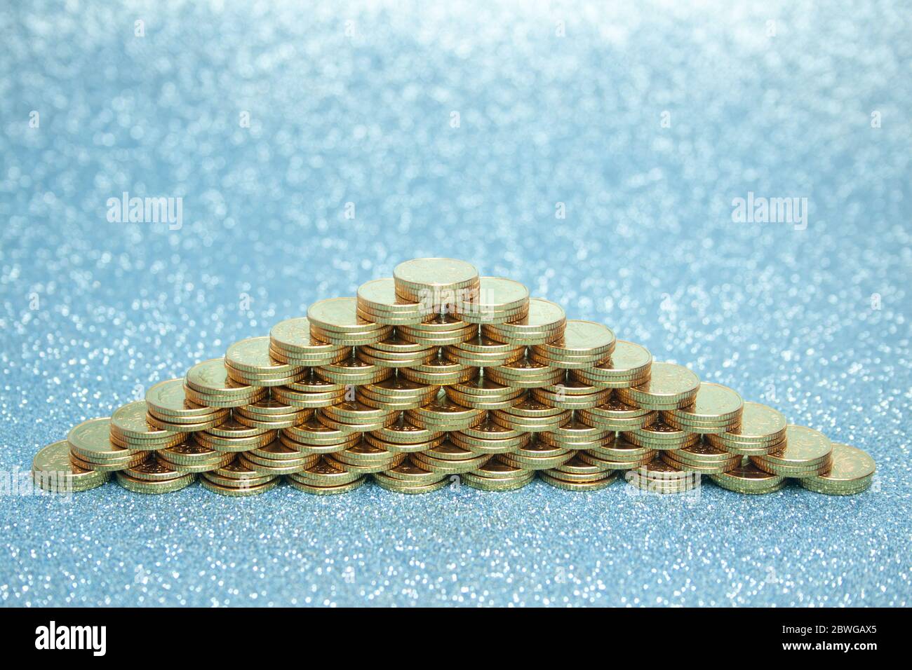 Pyramid of stacks of gold coins on a blue background Stock Photo - Alamy