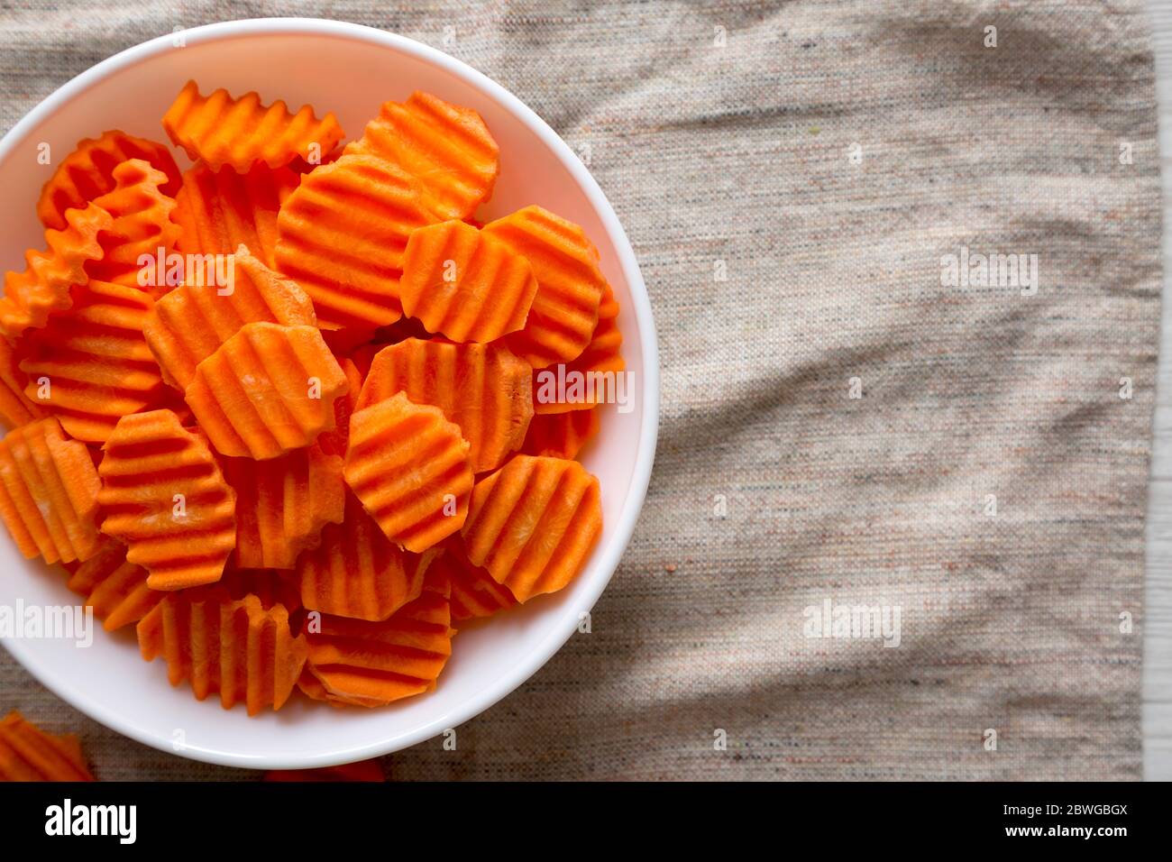 Fresh Raw Organic Carrot Chips in a white bowl on cloth, top view. From ...