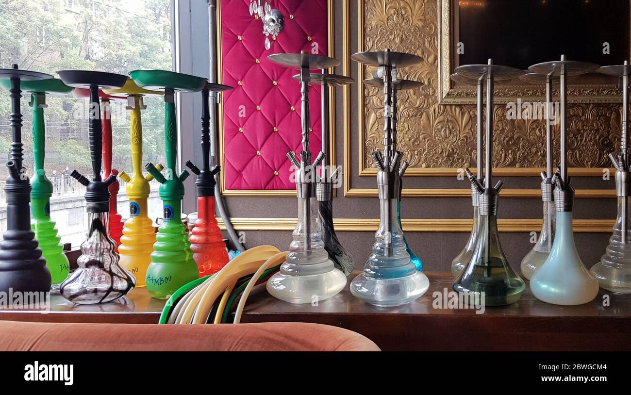 Group of modern glass hookah appliance on a wooden stand. Restaurant ...