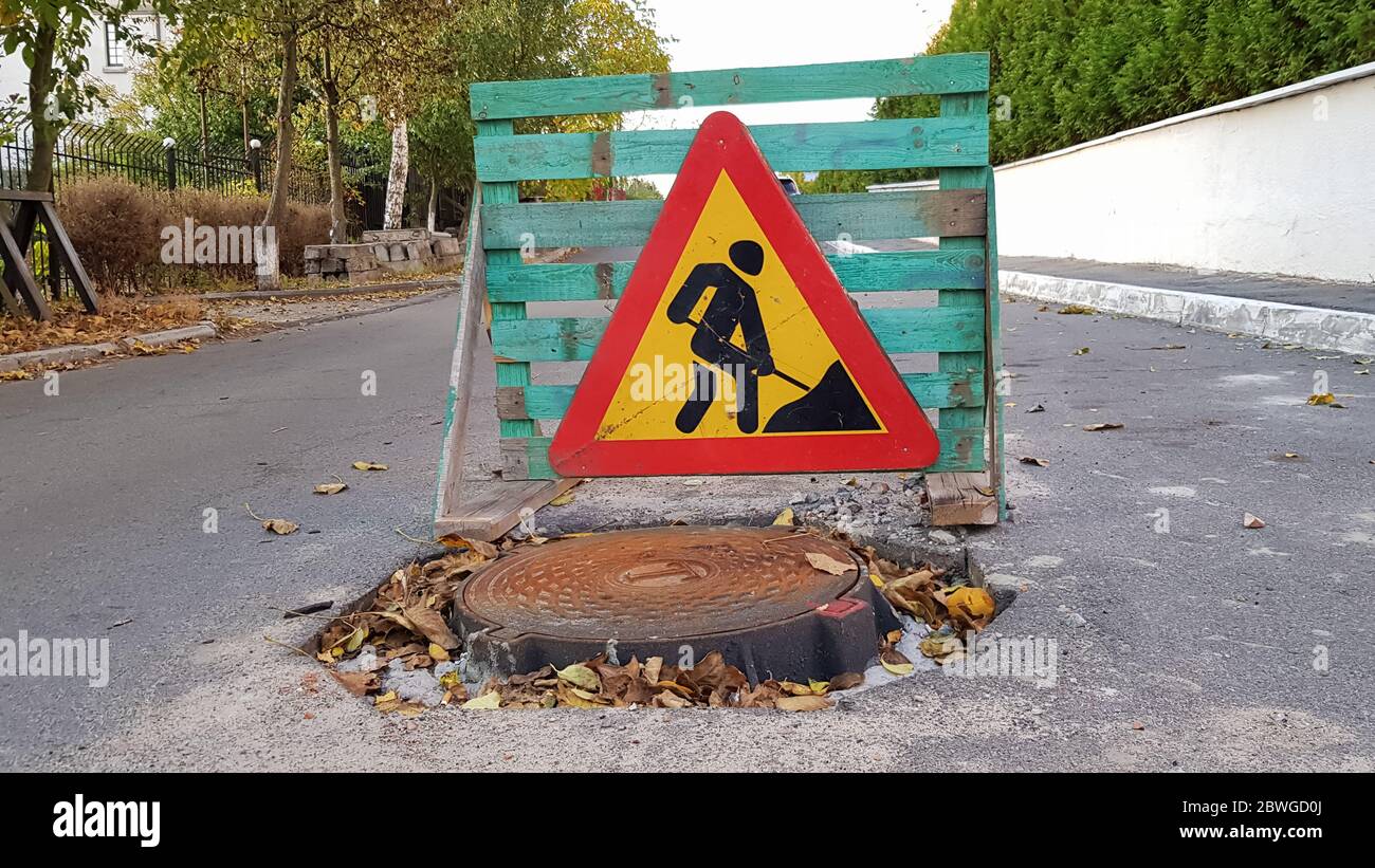 Road repair. Sewer manhole on the roadway. Triangular warning car ...