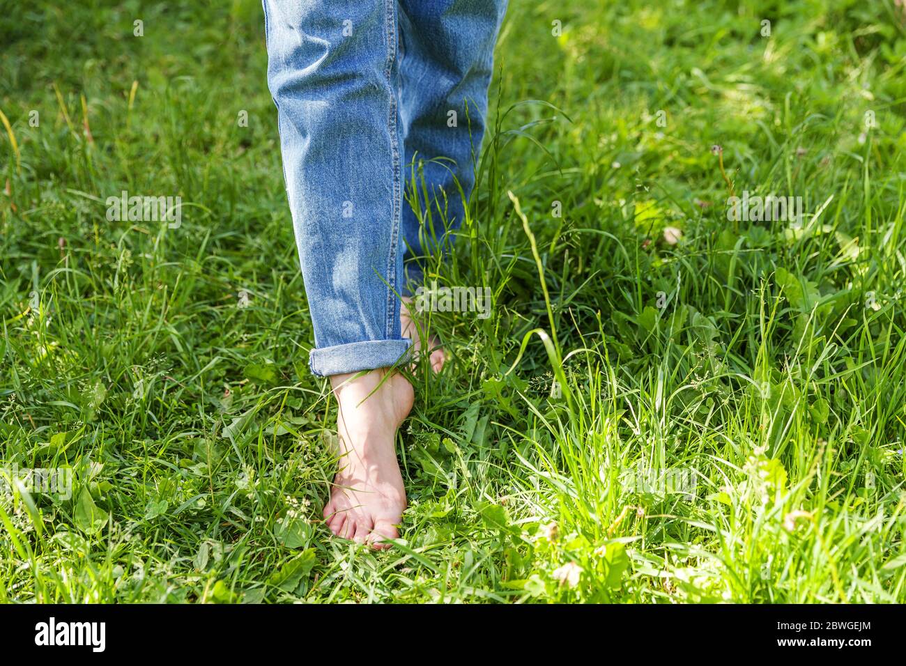 Two beautiful female feet walking on grass in sunny summer morning ...