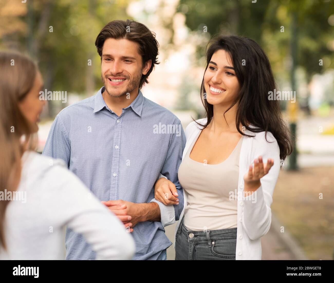 Girl Talking With Married Couple Of Friends Walking Outside Stock Photo ...