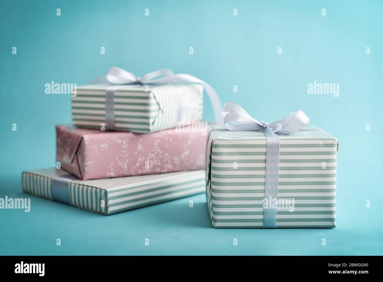 Several gift striped boxes with grey ribbon on blue background closeup ...