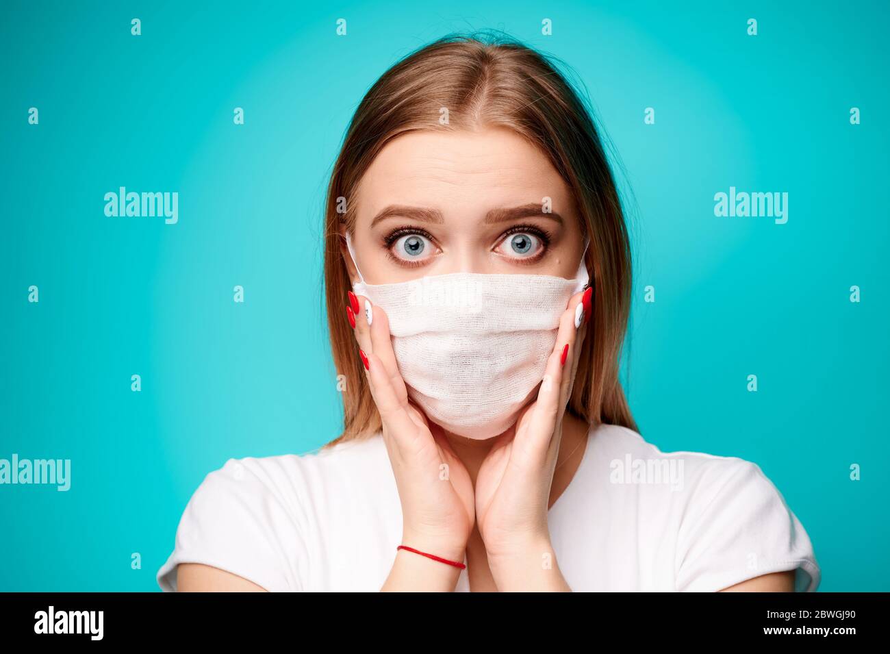 Surprised woman in aseptic mask in isolated blue background Stock Photo ...