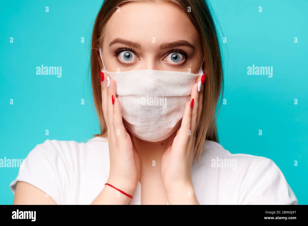 Surprised woman in aseptic mask in isolated blue background and looking ...