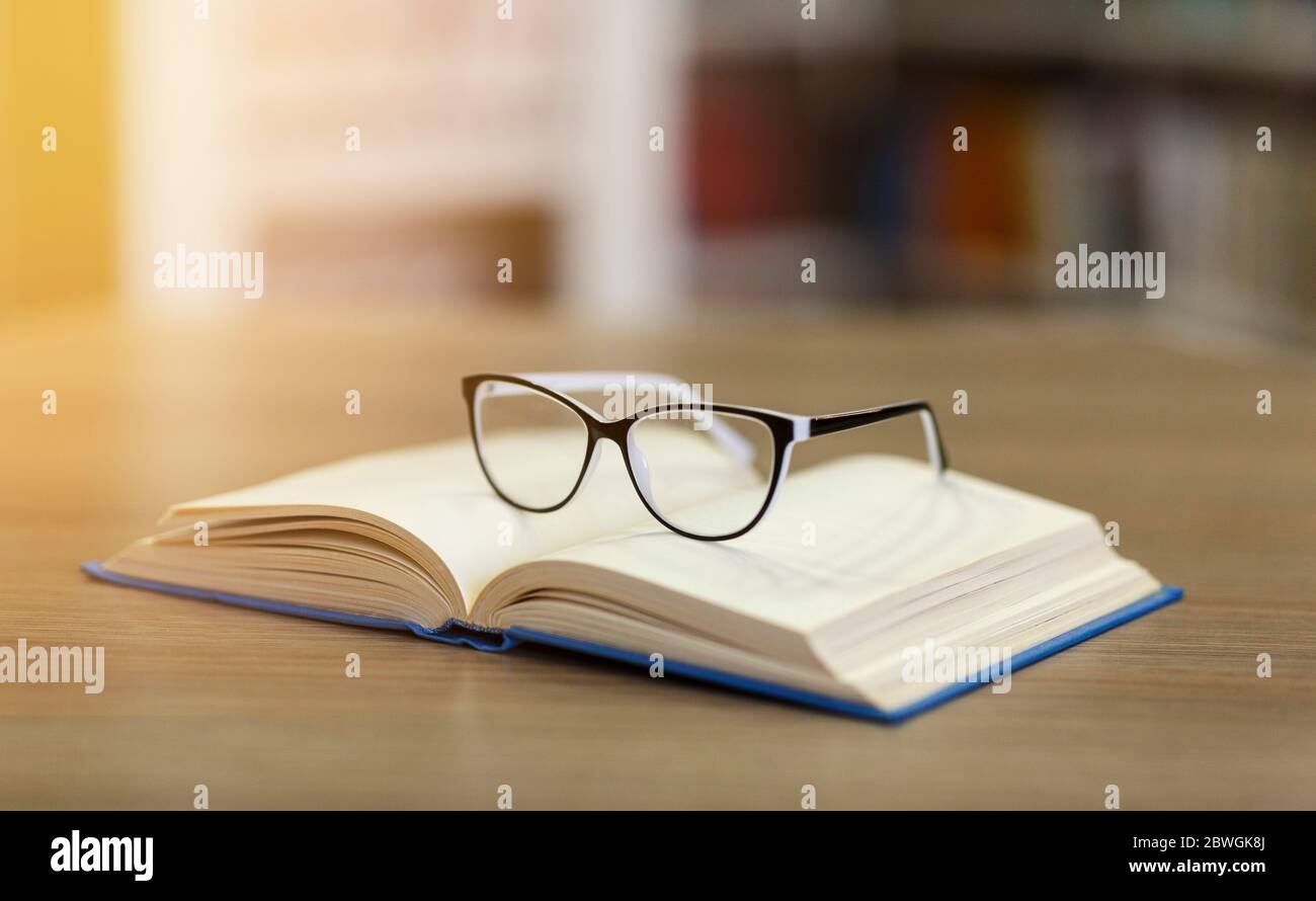 Opened book close up with glasses and sun light Stock Photo - Alamy