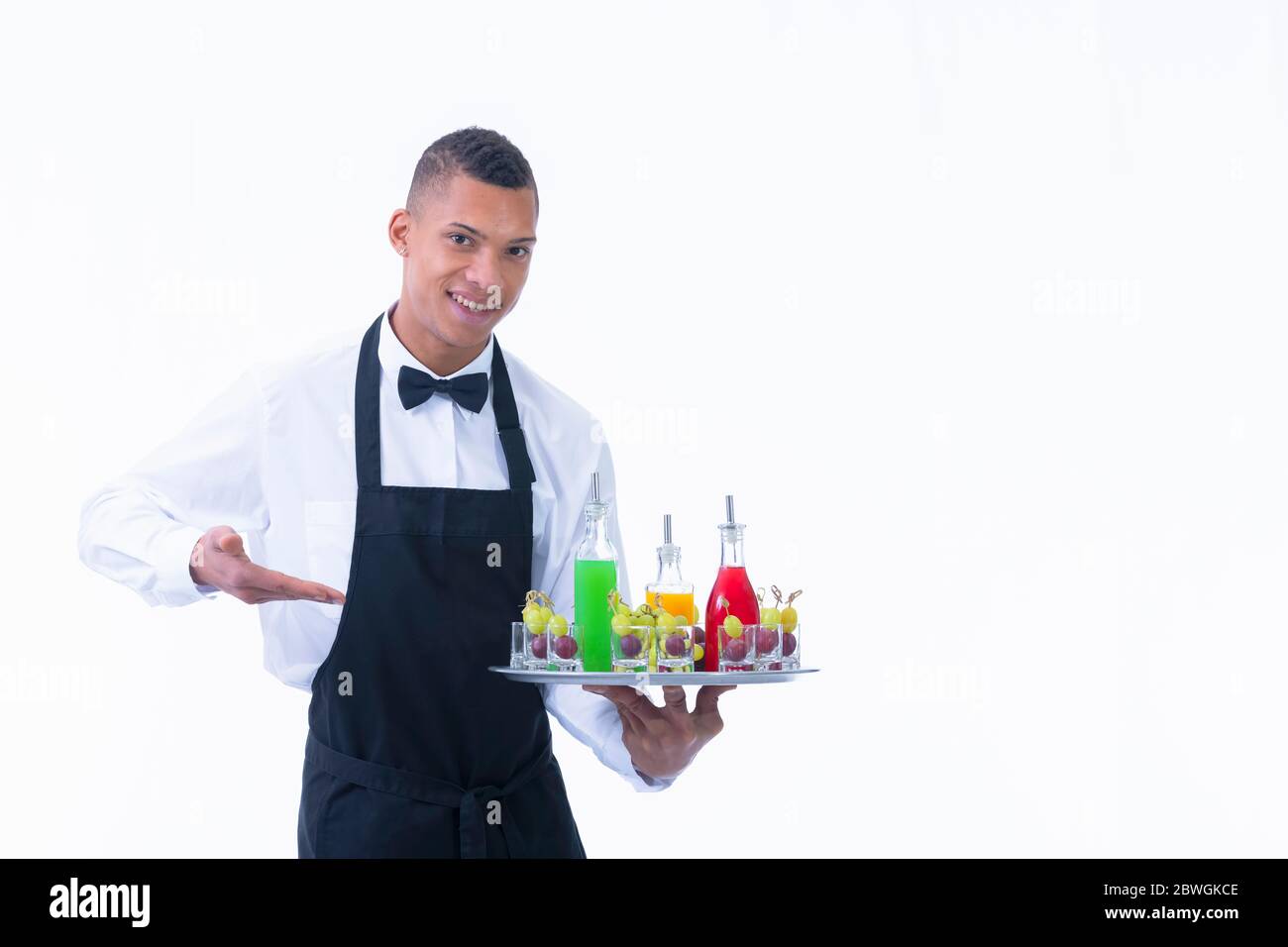 Handsome young waiter holding a tray with assorted liquor bottles and ...
