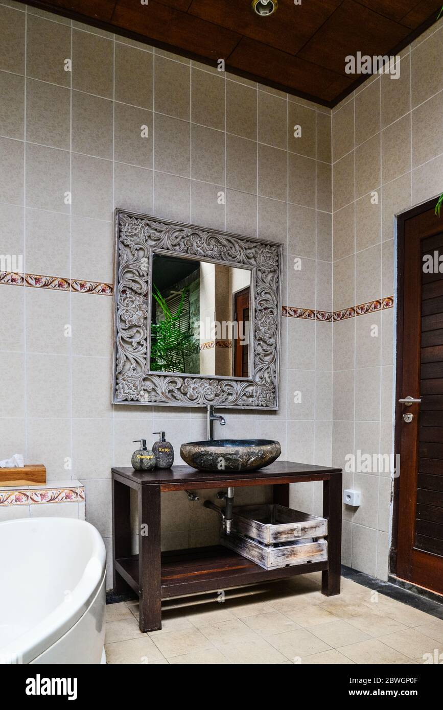 Bathroom with washbasin, mirror and bath in traditional balinese style ...