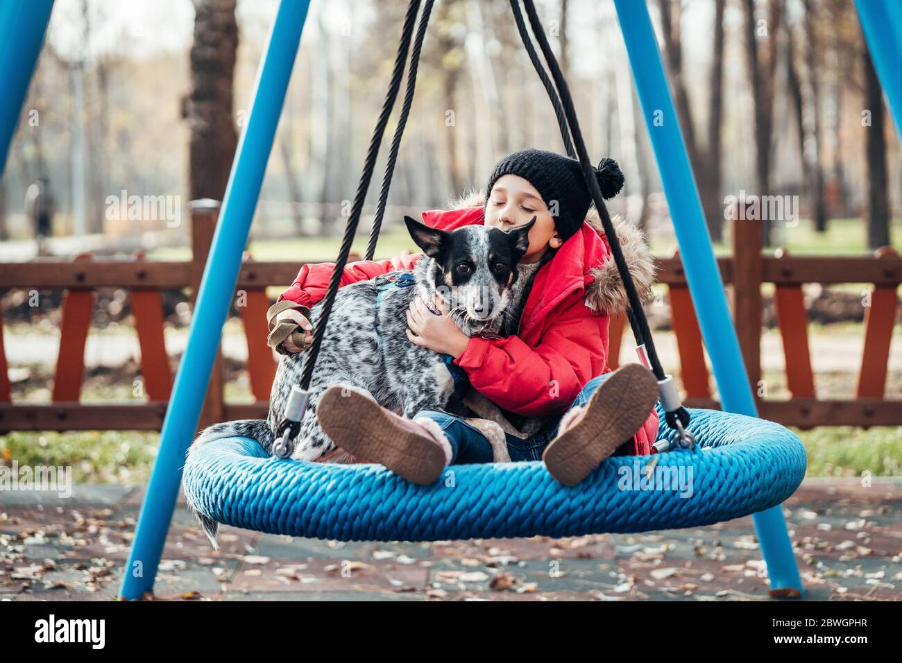 Happy child girl on swing. Little girl on a swing hugs her dog Stock ...