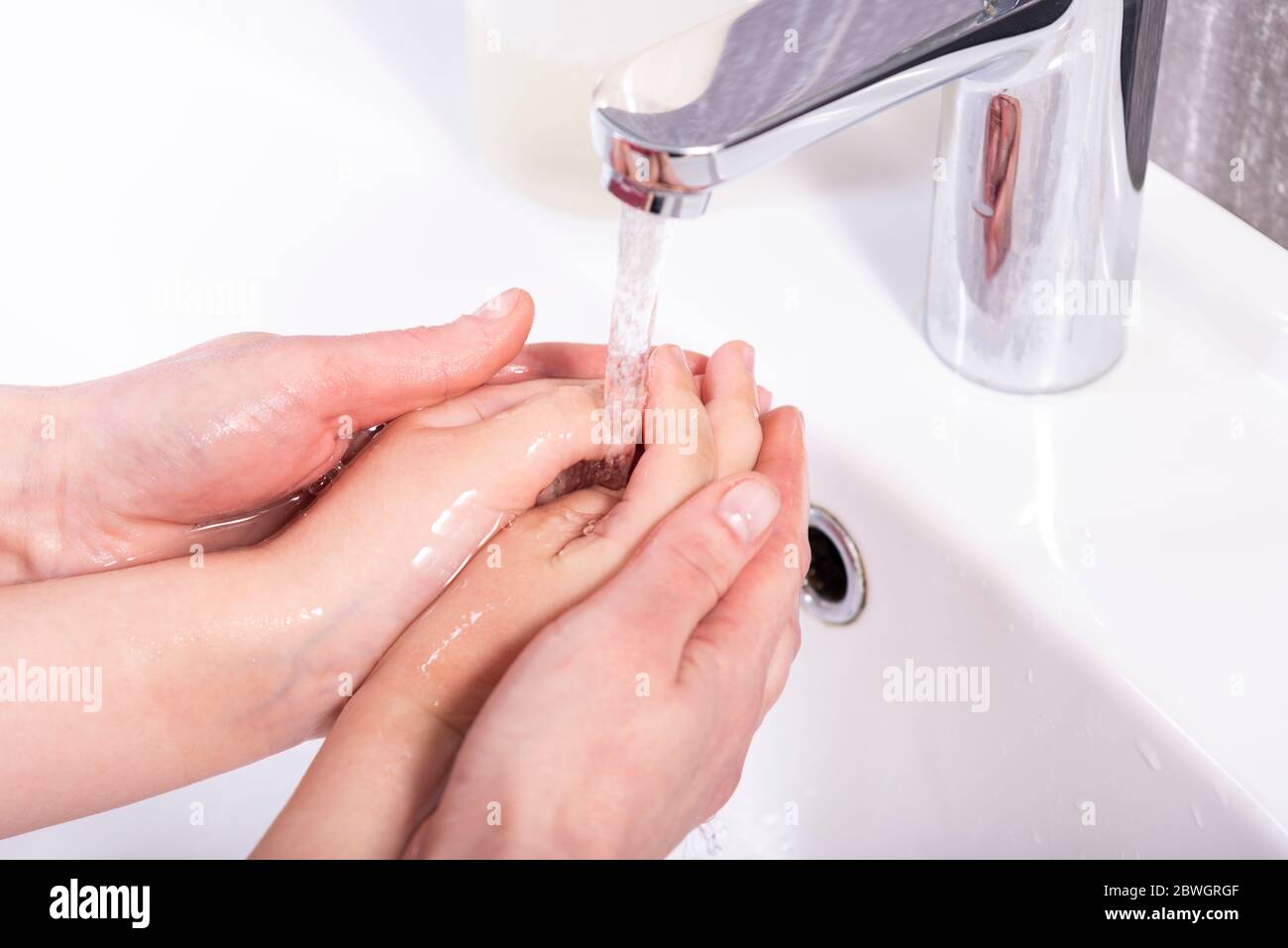 Mom washes her baby s hands under the tap in a modern bathroom Stock ...
