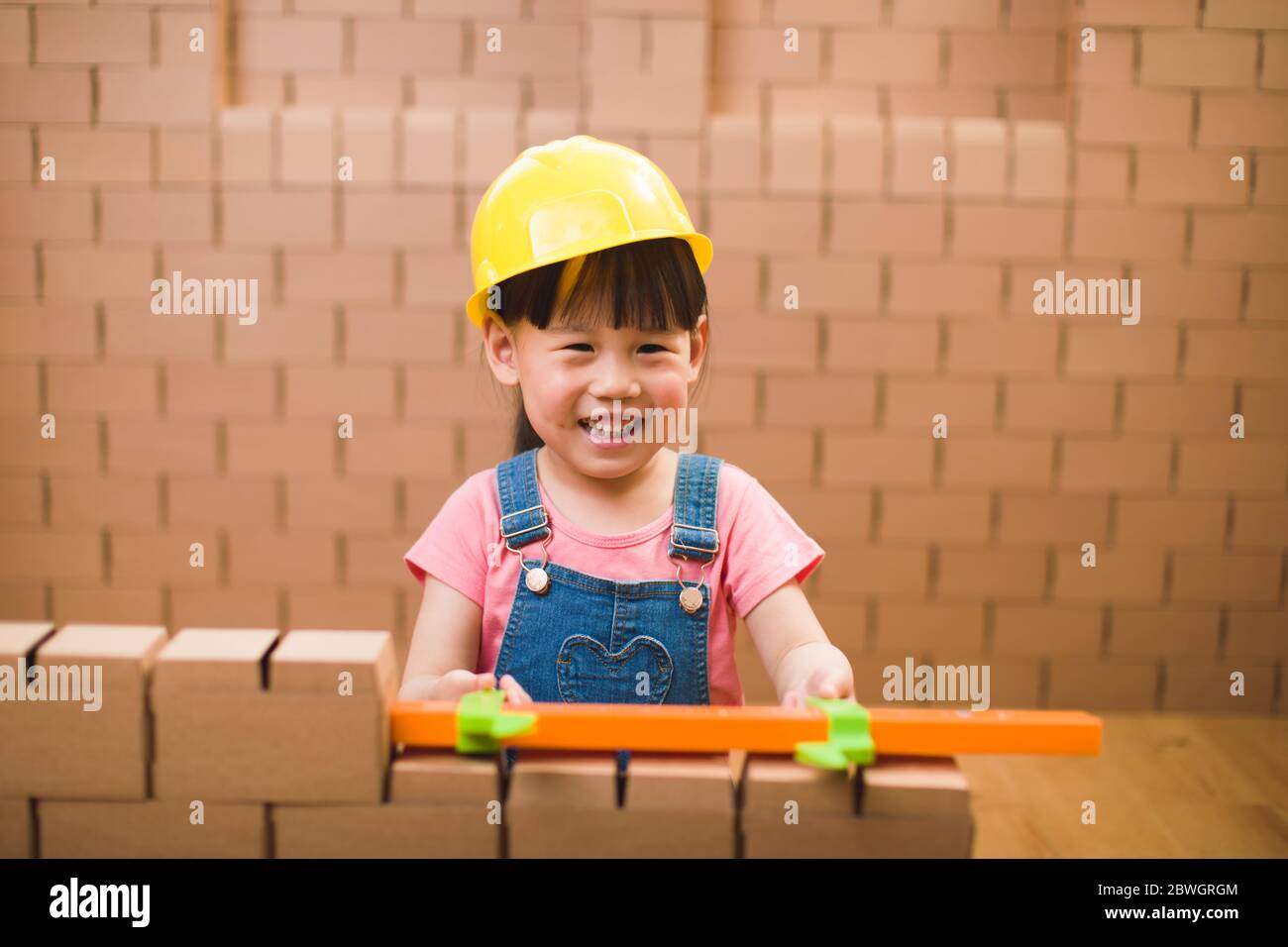 toddler girl pretend play builder role by using cardboard blocks Stock ...