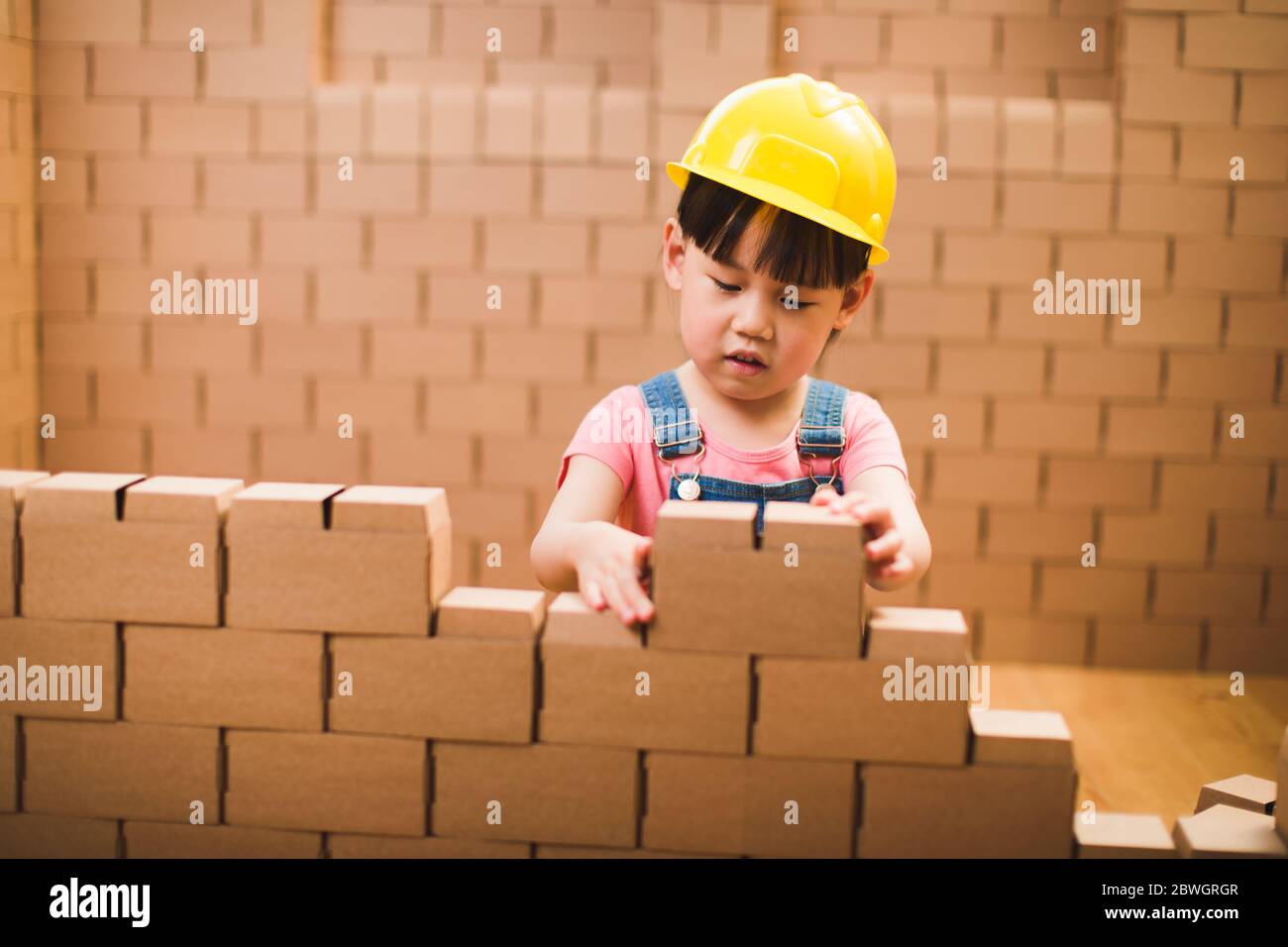 toddler girl pretend play builder role by using cardboard blocks Stock ...