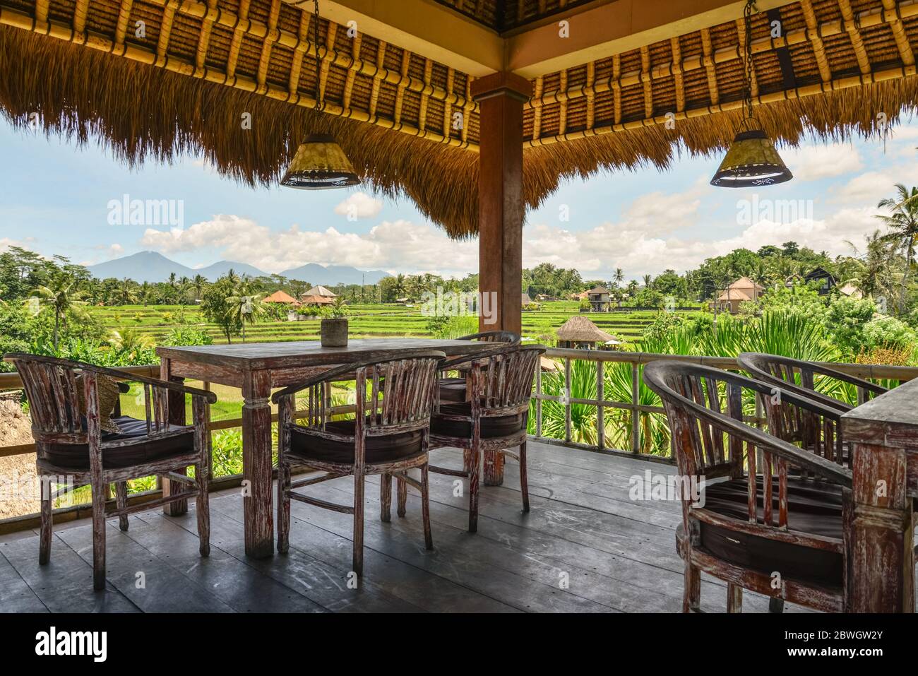 Wooden tables and chairs in empty tropical cafe next to rice terraces ...