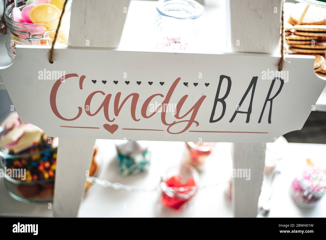 Candy bar lettering on white stand. Various sweets and gummy candies in ...