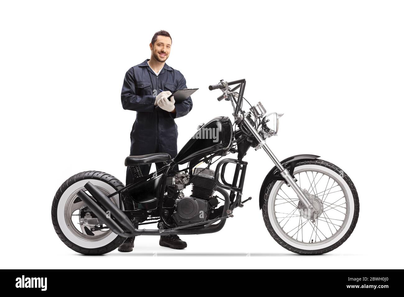 Motorbike mechanic standing behind a chopper and holding a clipboard ...