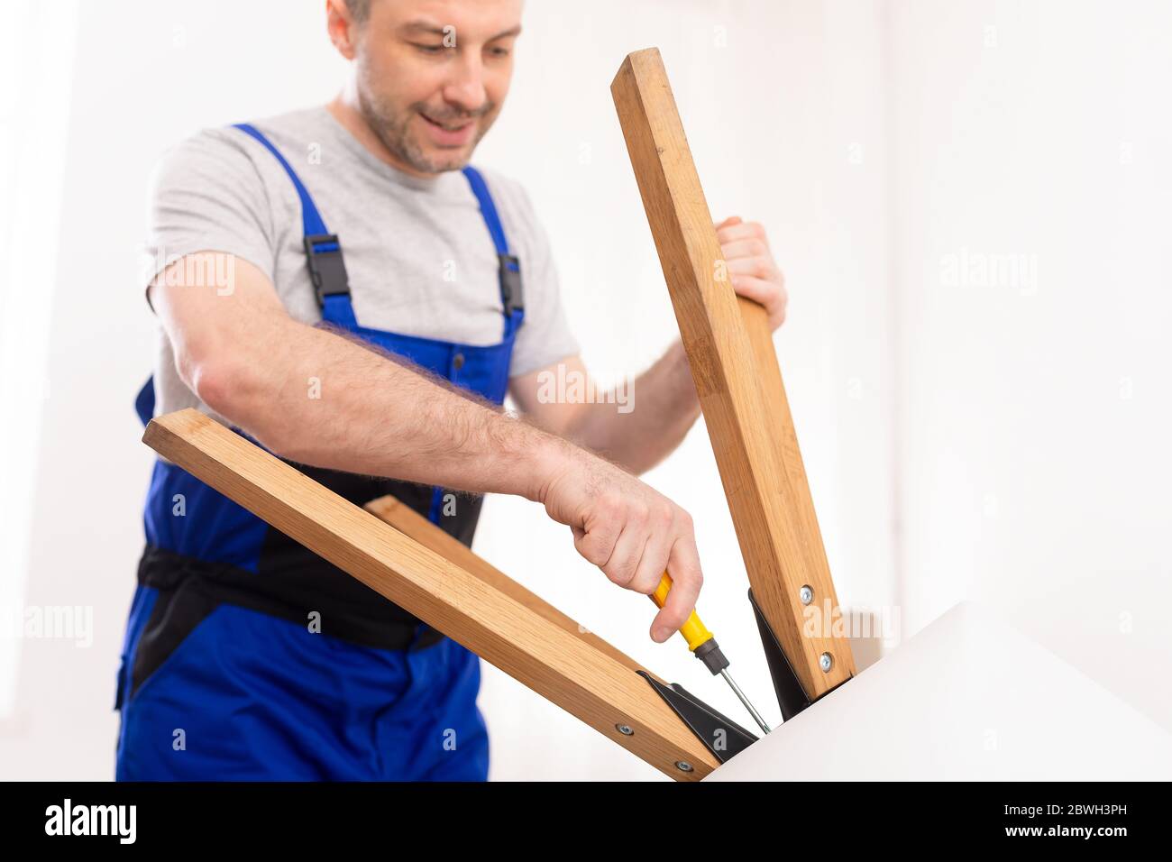 Repairman Assembling Table Using Screwdriver Working Standing Indoors