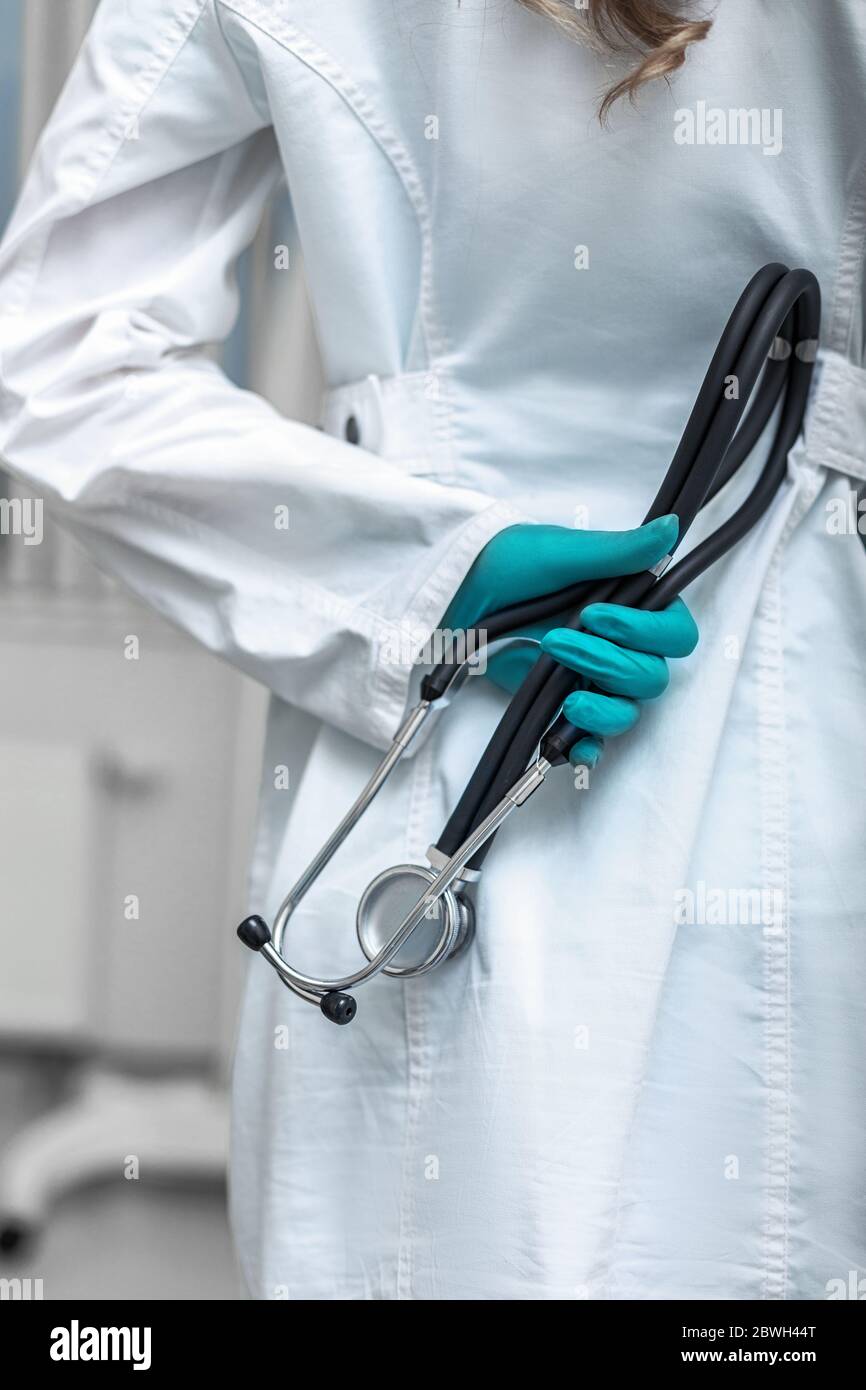 Doctor's hand in white coat holding a phonendoscope on the background ...