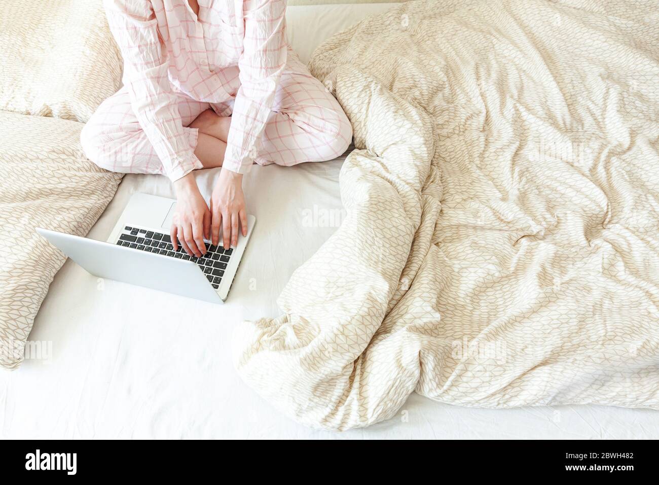 Mobile Office at home. Young woman in pajamas sitting on bed at home ...
