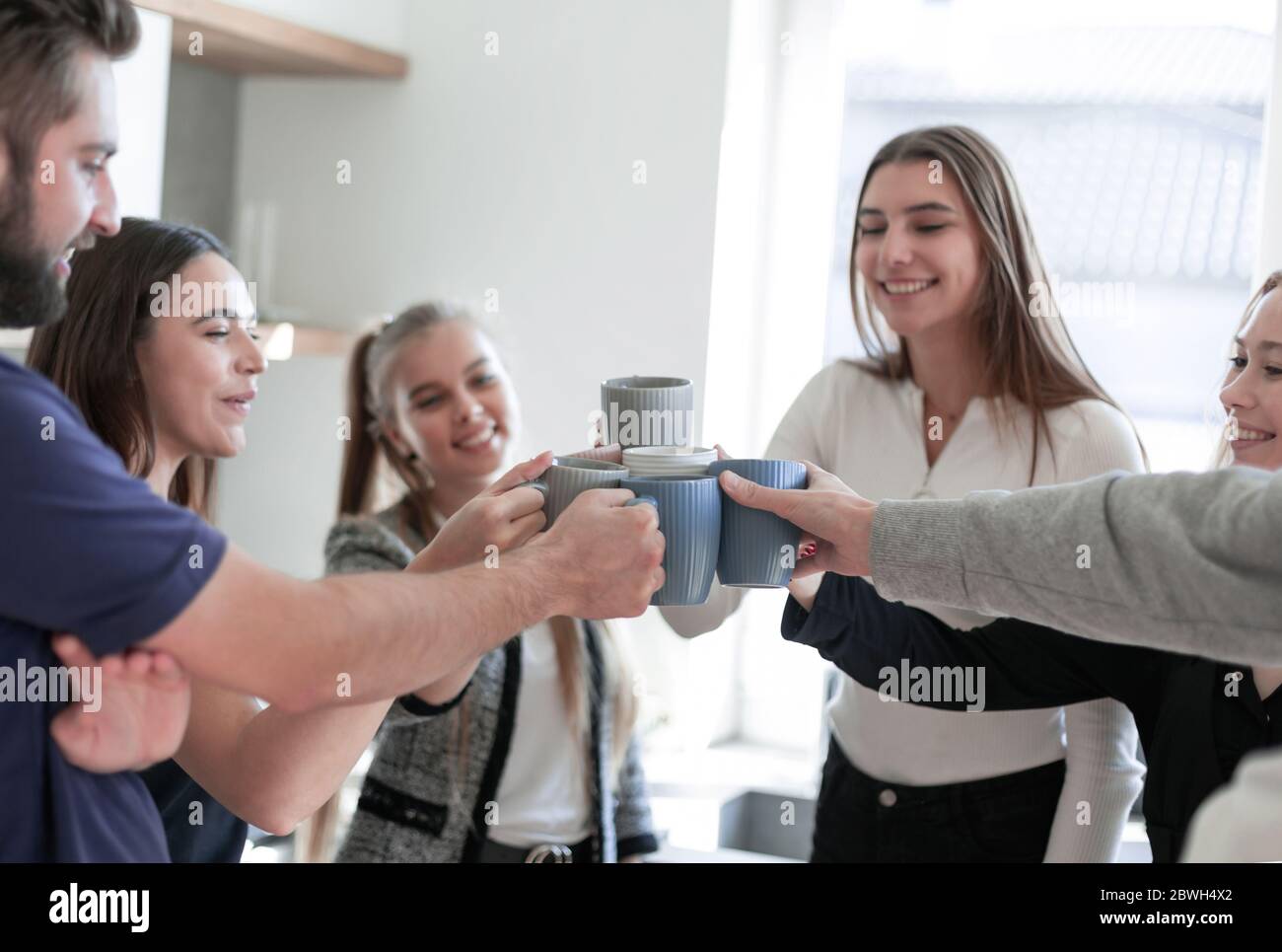 Smiling friends meeting with mugs of tea Stock Photo - Alamy