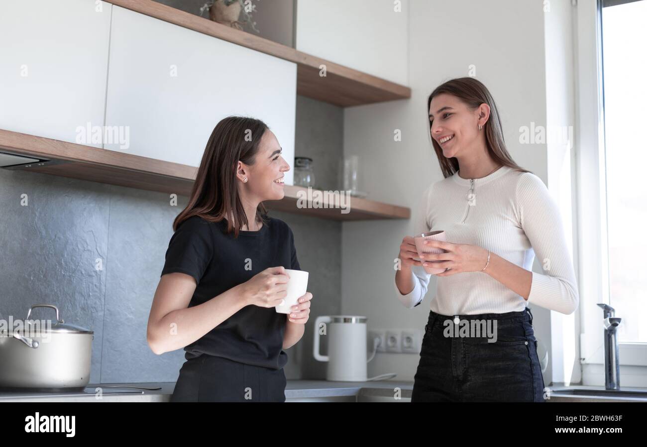 Two young laughing women standing at kitchen and enjoy Stock Photo - Alamy