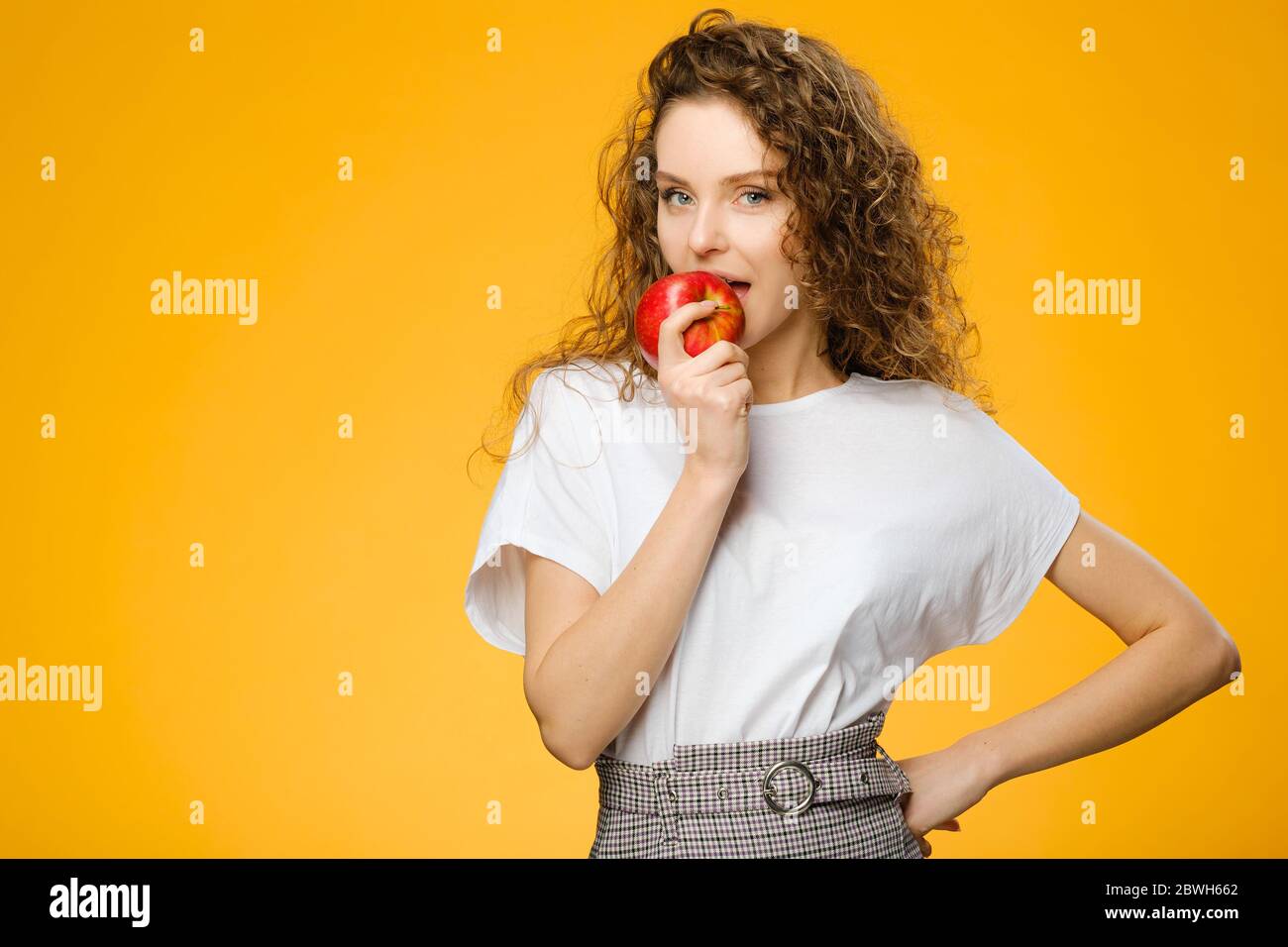 Closeup portrait of pretty caucasian girl with curly hair and red apple ...