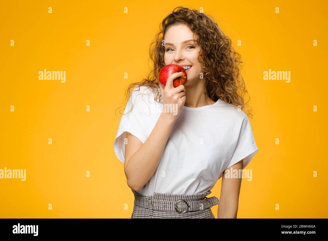Closeup portrait of pretty caucasian girl with curly hair and red apple ...