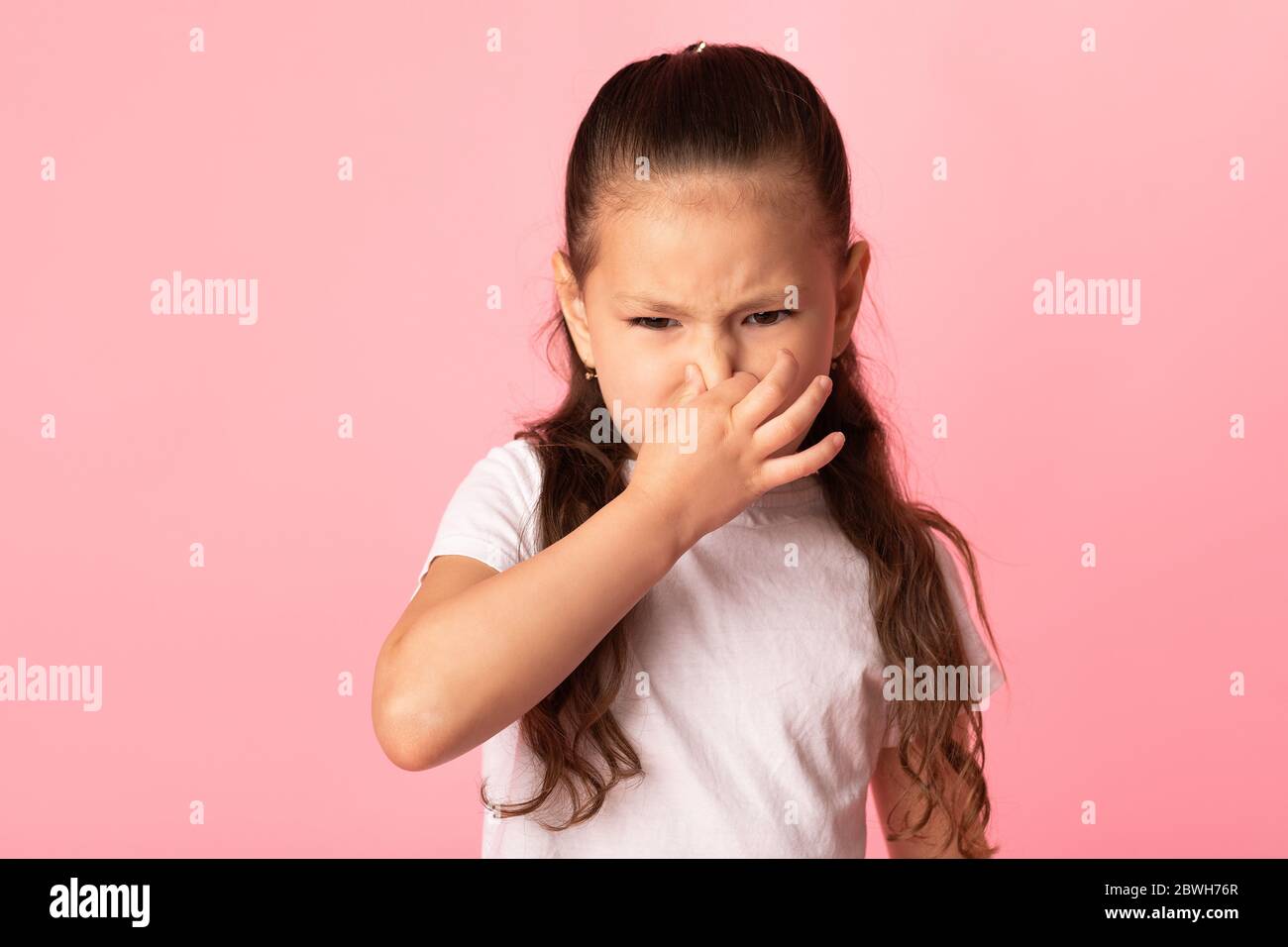 Shocked girl smelling something stinky at studio Stock Photo - Alamy