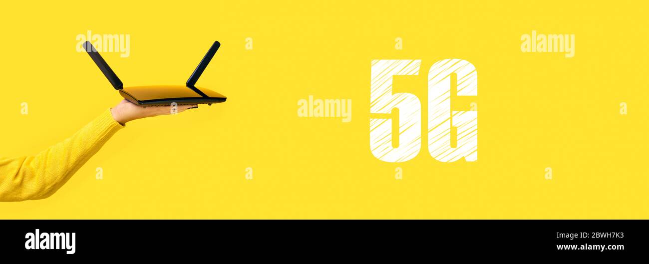 black wifi router on hand over yellow background, 5g concept, panoramic ...