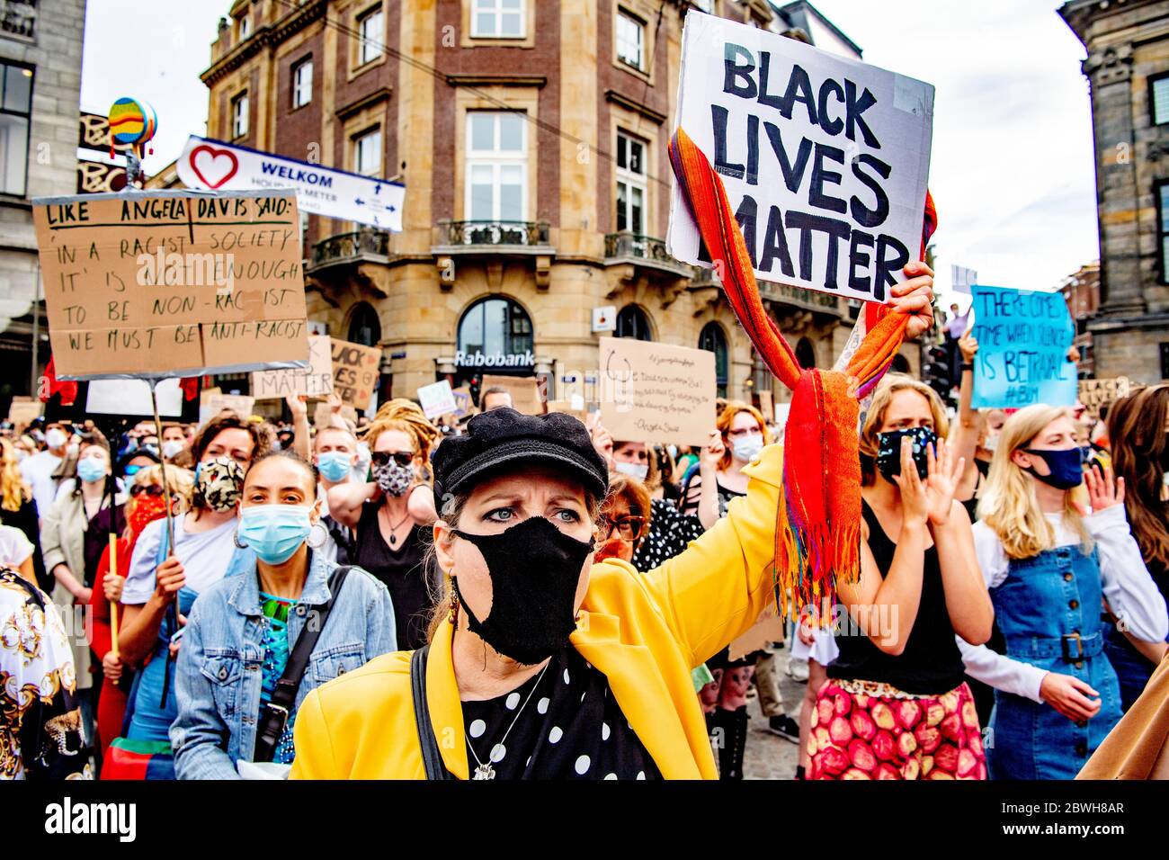 A woman, wearing a facemask holds a placard saying Black Lives Matter ...