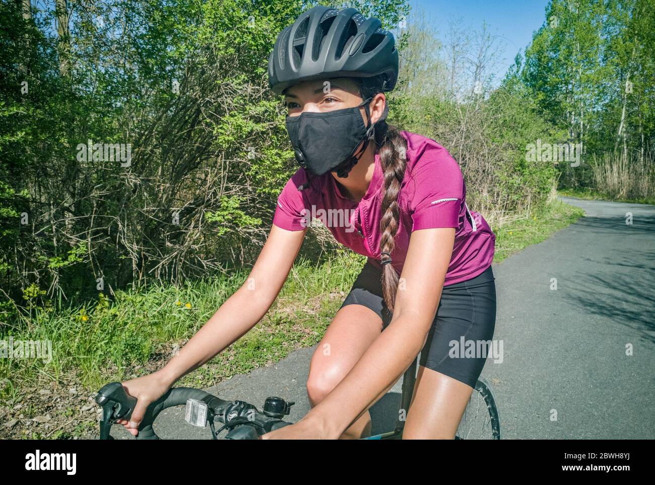 Sport cyclist woman biking on road bike wearing face mask for Covid-19 ...