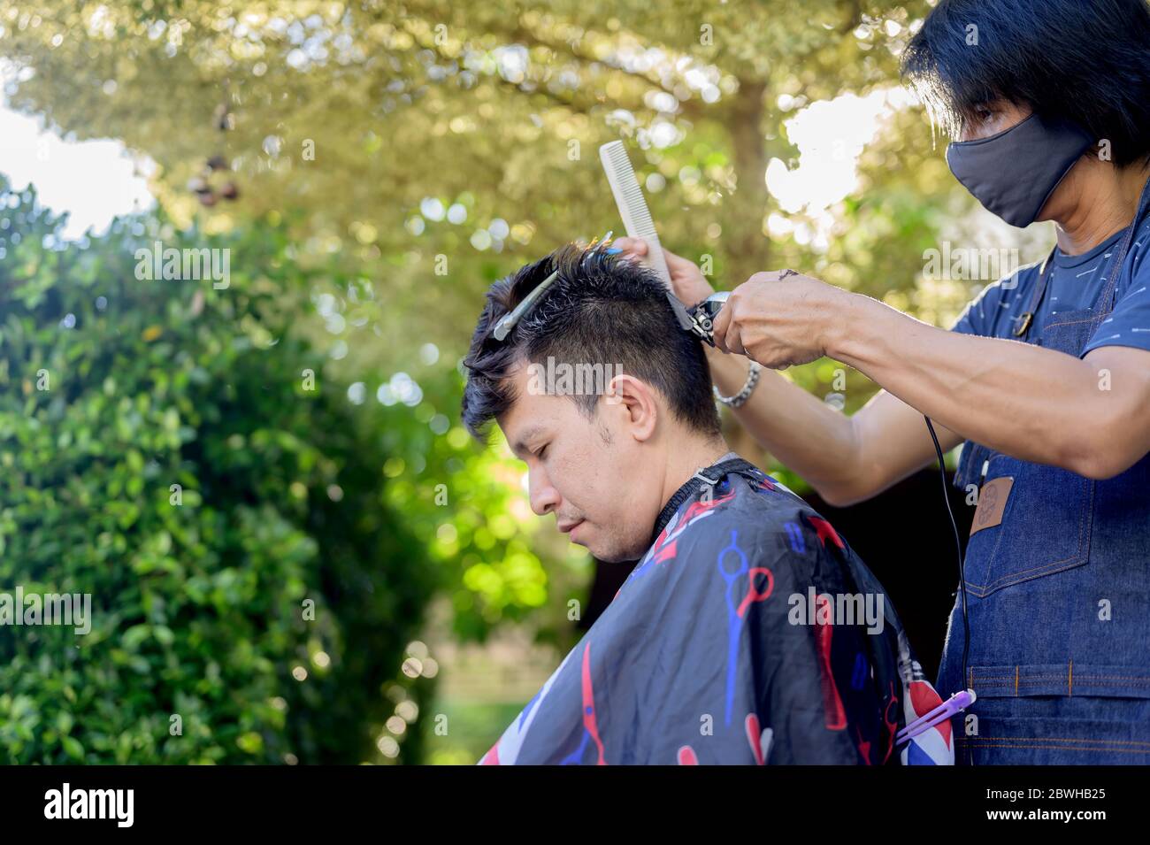 Asian making haircut at home garden. Learning online barber courses ...
