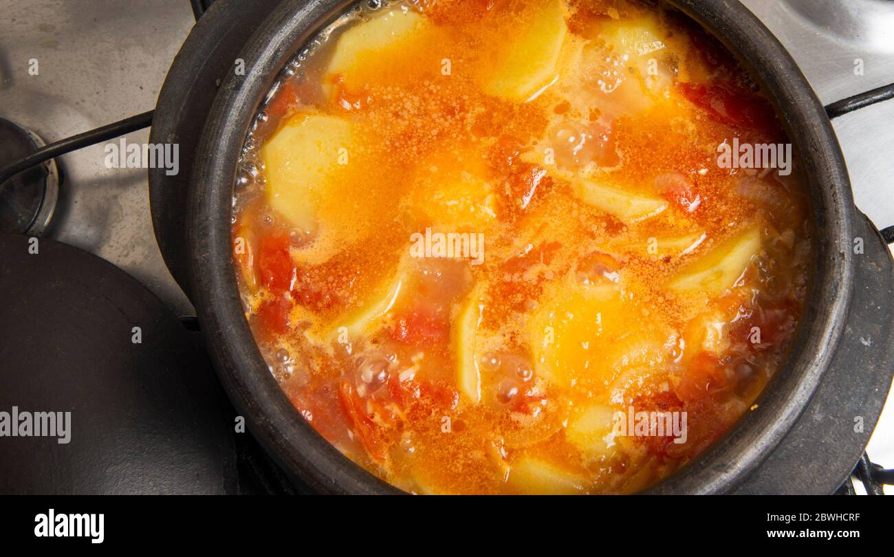 fish being cooked in a clay pot in tomato sauce Stock Photo - Alamy
