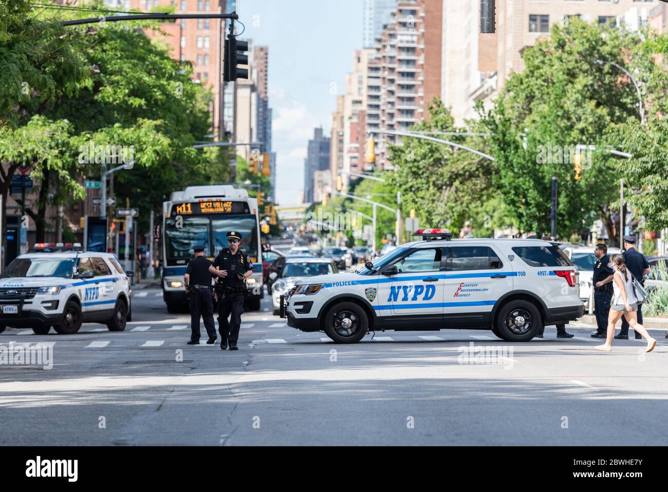Officers of the NYPD blocking off the street to stop cars and control ...