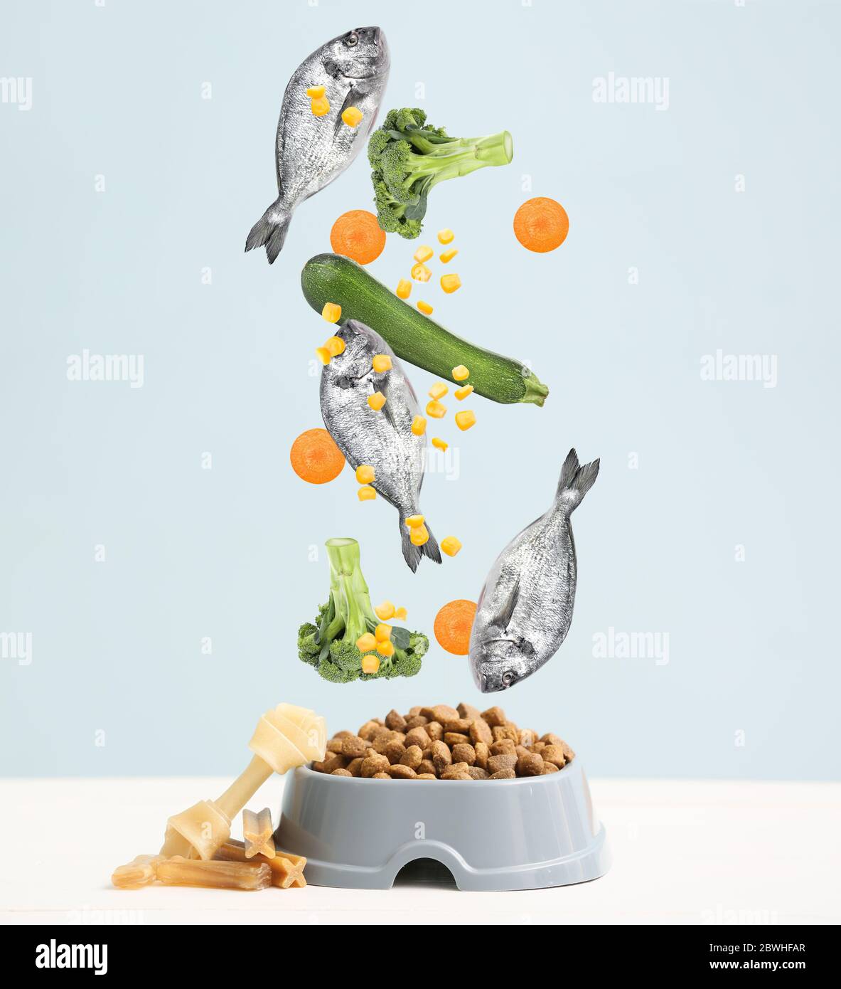 Different pet food falling into bowl against light background Stock ...