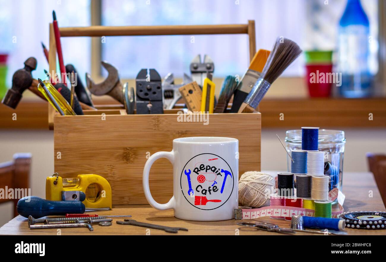 Repair Cafe logo on a cup surrounded by repair tools on table in cafe ...