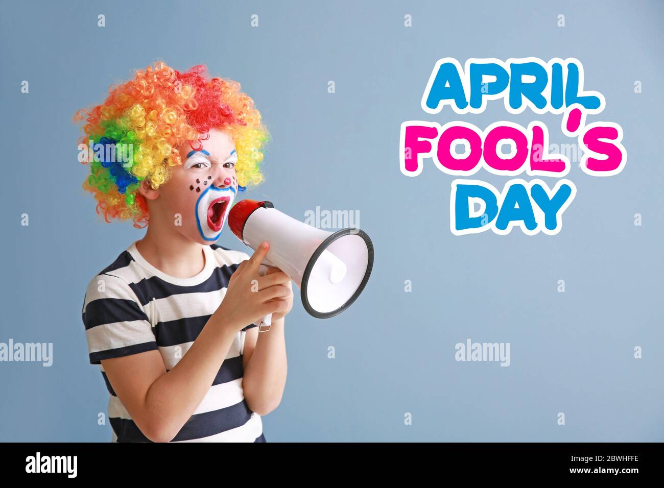 Cute little boy with clown makeup and megaphone on color background ...