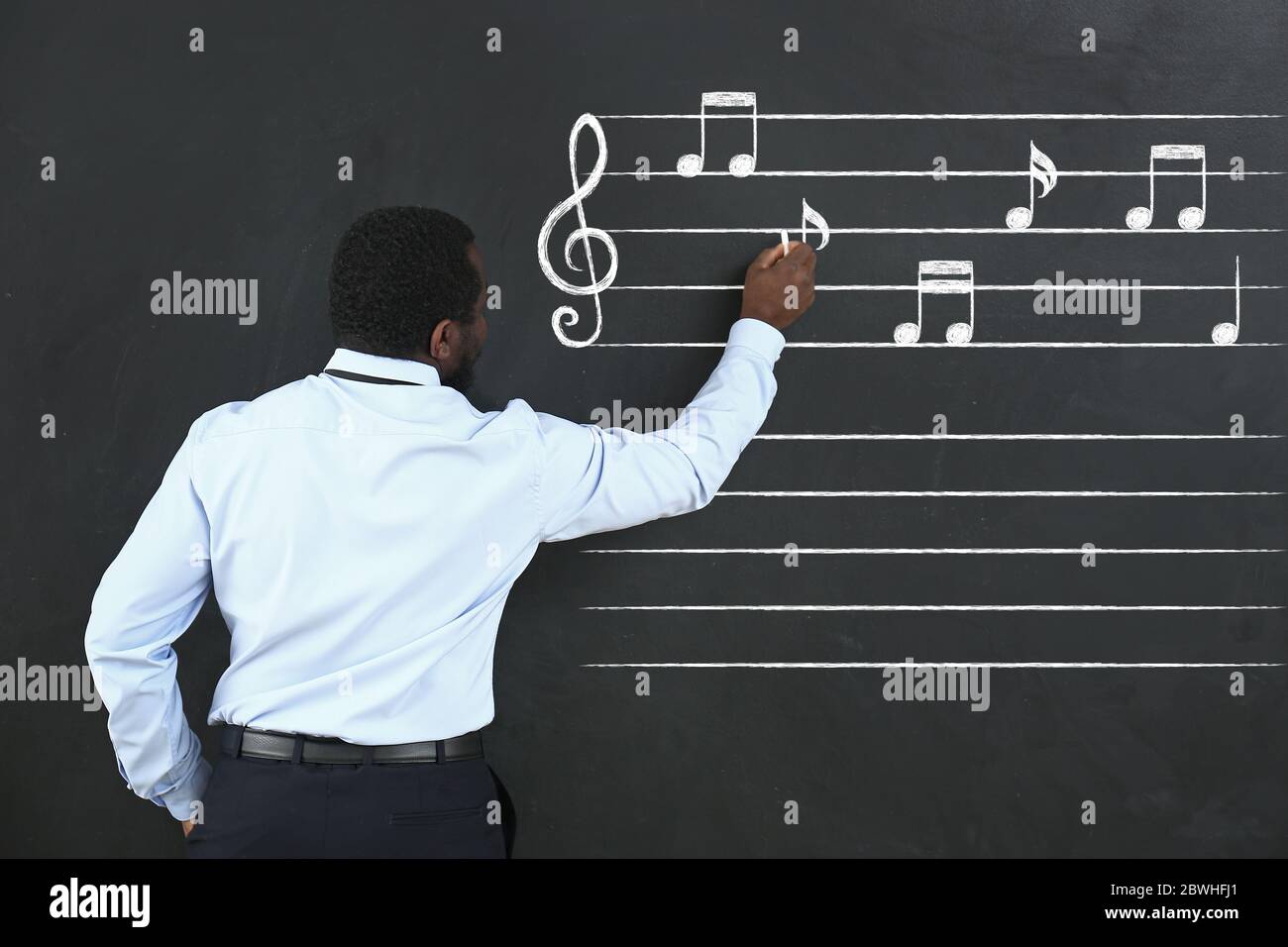 African-American music teacher writing on blackboard in classroom Stock ...