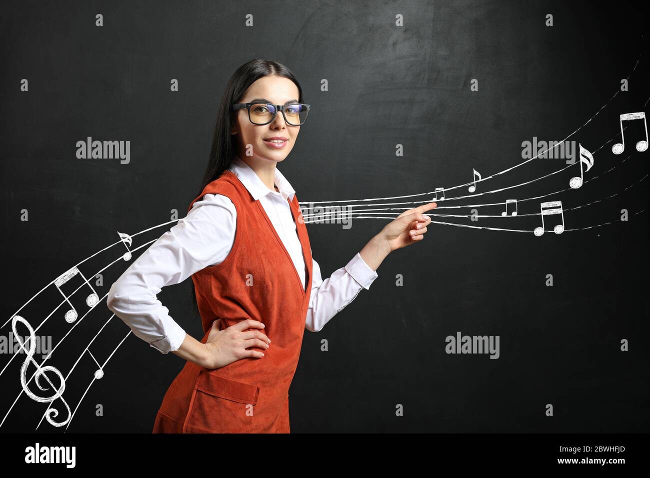 Beautiful music teacher near blackboard in classroom Stock Photo - Alamy