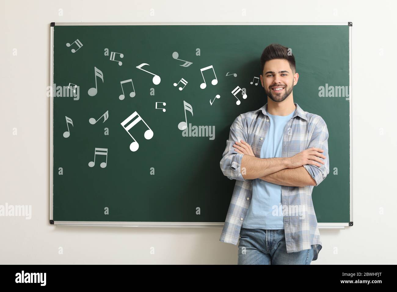 Handsome music teacher near blackboard in classroom Stock Photo - Alamy