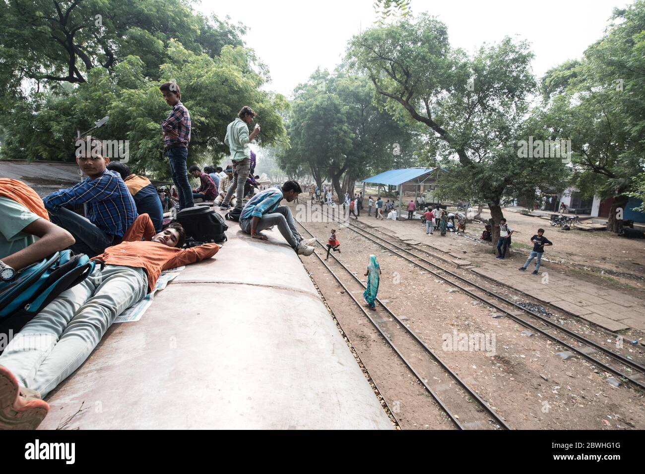 Men on top of overcrowded train passes through a small town in Madhya ...