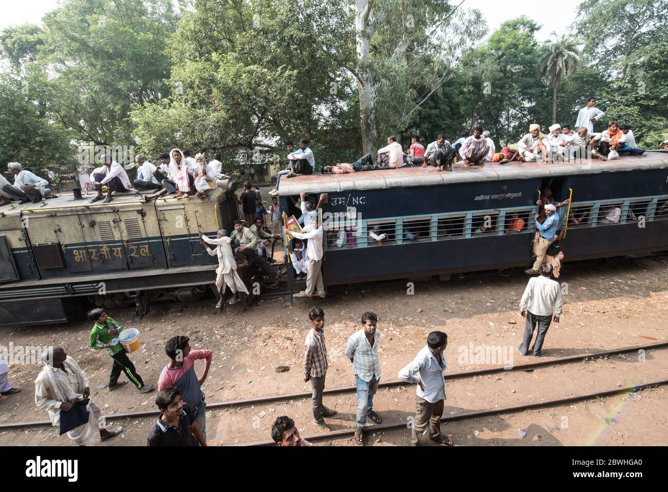 Passengers on top of overcrowded train at a train station in rural ...