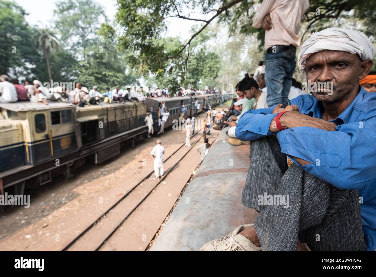 Passengers on top of overcrowded train at a train station in rural ...