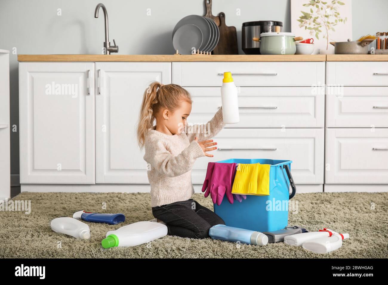Little girl playing with cleaning supplies at home Stock Photo - Alamy
