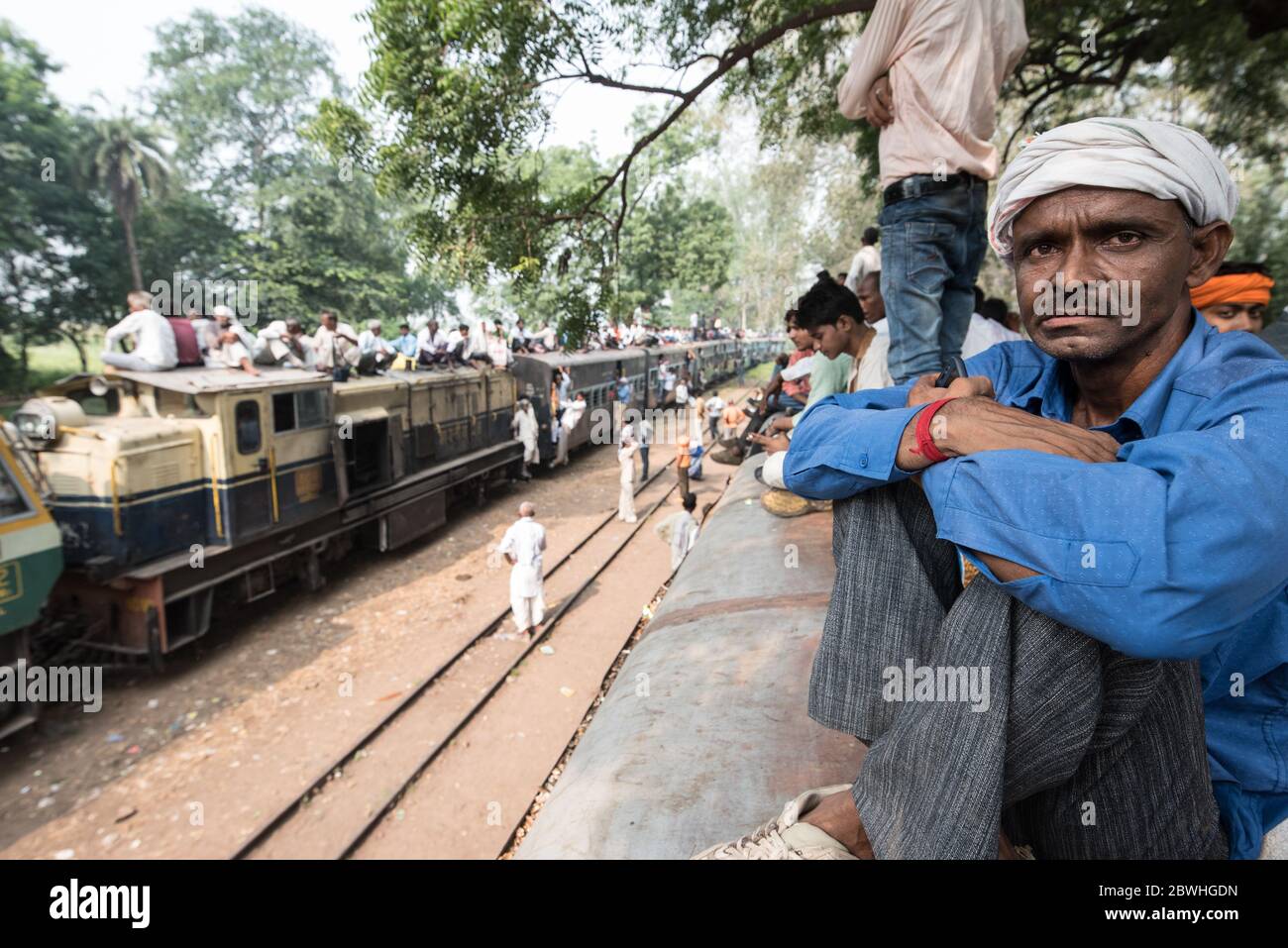 Passengers on top of overcrowded train at a train station in rural ...