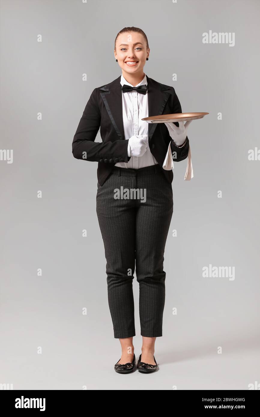 Beautiful female waiter on grey background Stock Photo - Alamy