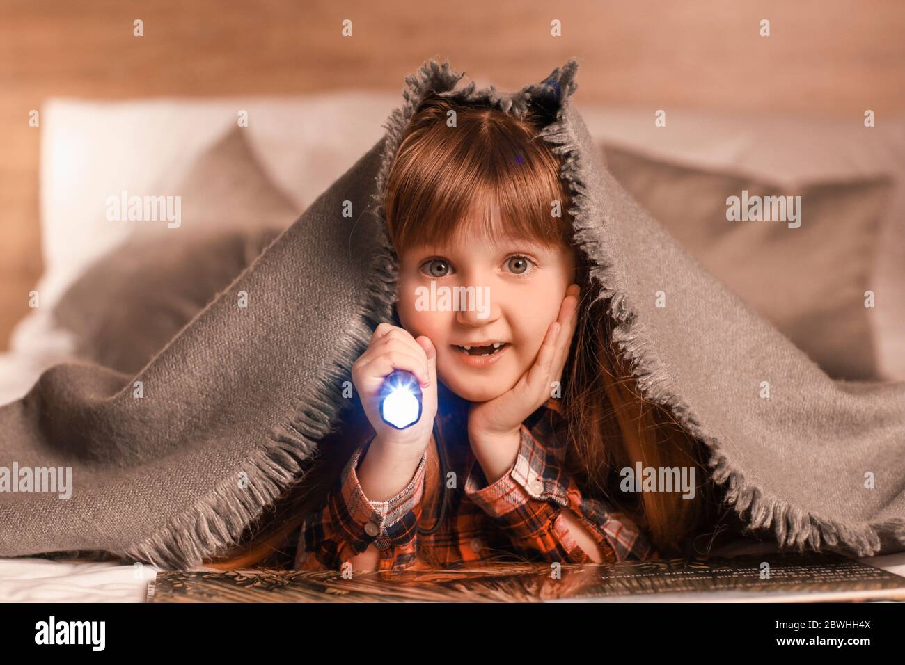 Little girl with flashlight reading book in evening Stock Photo - Alamy