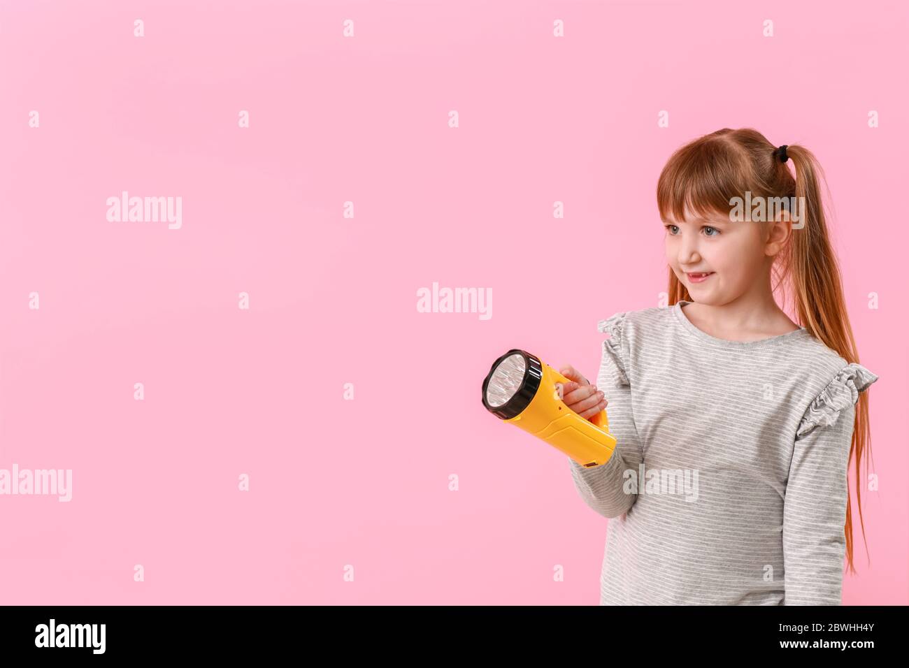 Little girl with flashlight on color background Stock Photo - Alamy