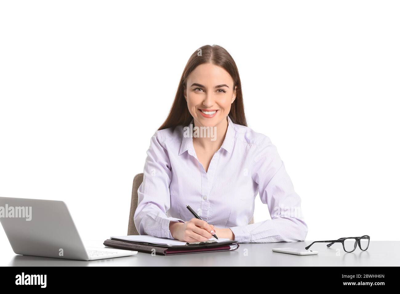Beautiful young secretary at table on white background Stock Photo - Alamy