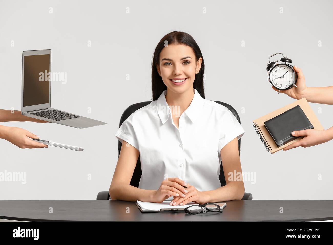 Beautiful young secretary with a lot of work at table on white ...