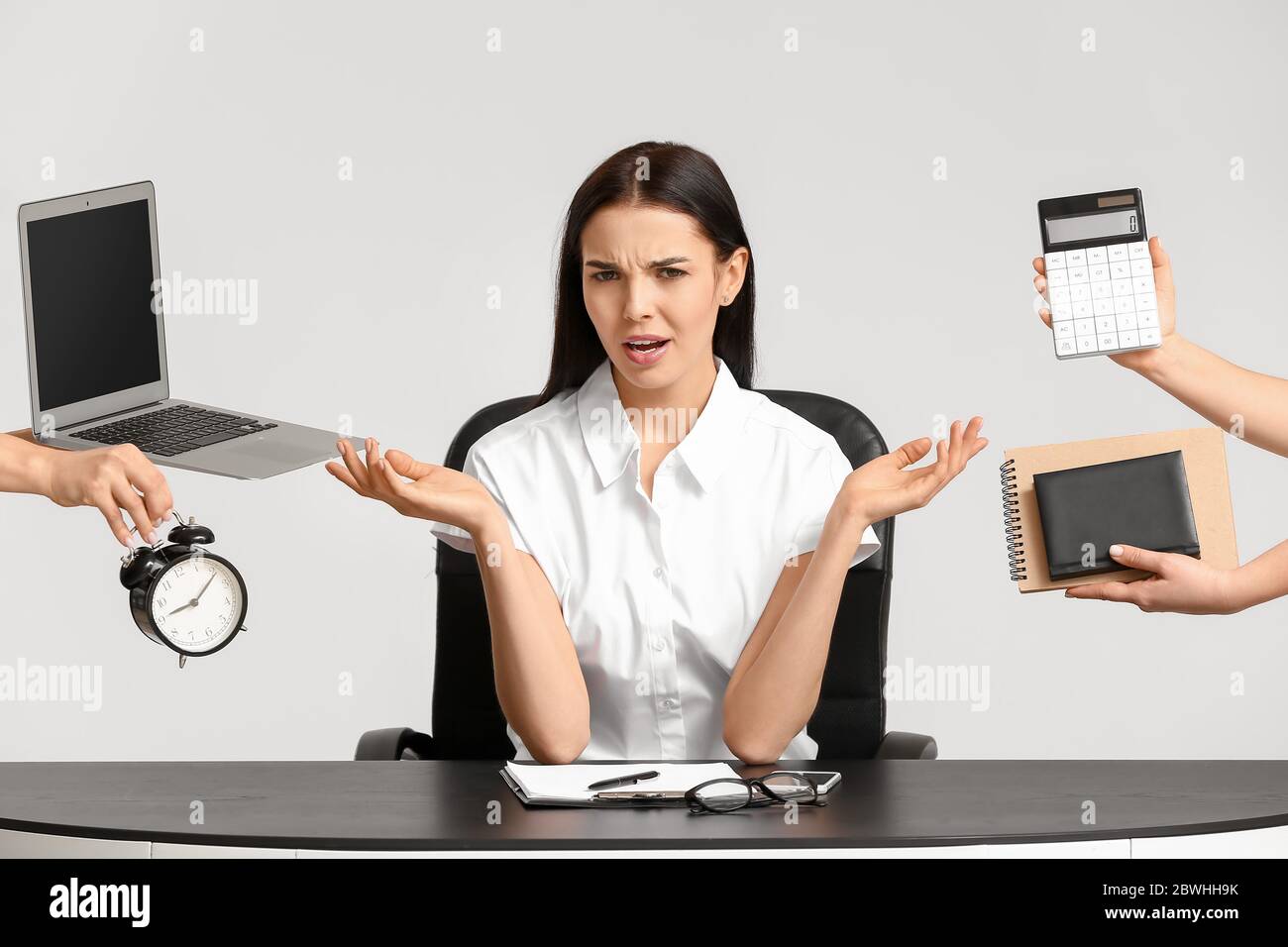 Stressed young secretary with a lot of work at table on white ...